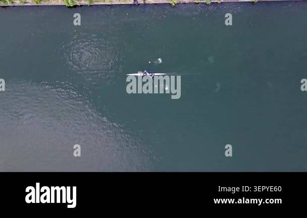 Aerial top-down drone view of rowers training along a calm canal ...