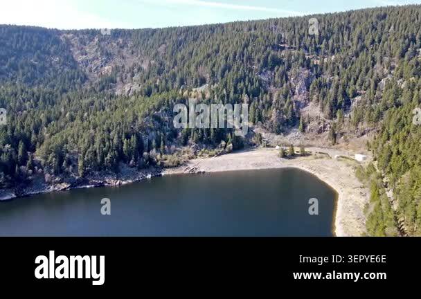 Aerial drone view of Lac Noir mountain lake with steep forested slopes ...