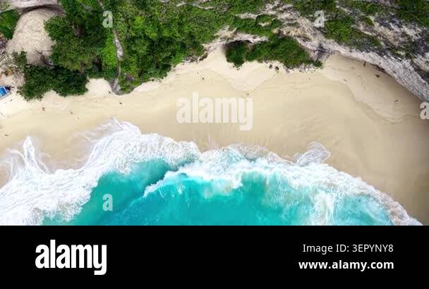 Drone top-down view of turquoise waves washing onto the sandy shore at ...