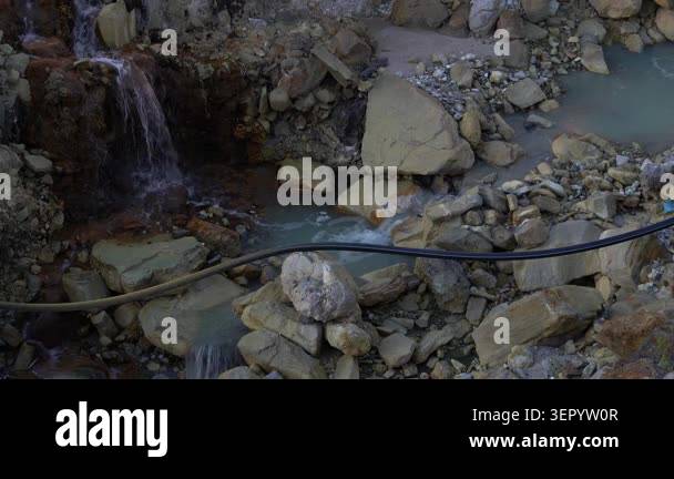 A small waterfall flowing over rocky terrain in a natural geothermal ...