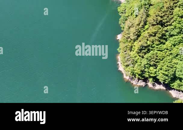 Clear blue water surrounding green forested shoreline Stock Video ...