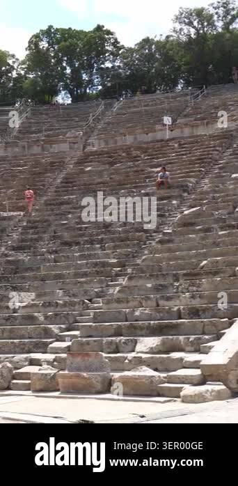 People admiring the vast stone tiers of a well preserved ancient Greek ...
