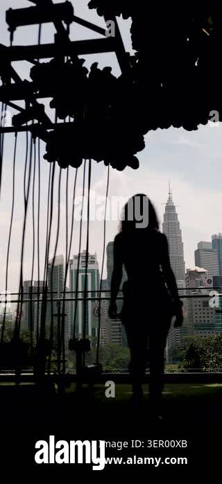 Womans silhouette stretches her arms, taking in the impressive Kuala ...
