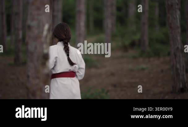 Focused young girl practicing martial arts in nature, showcasing ...