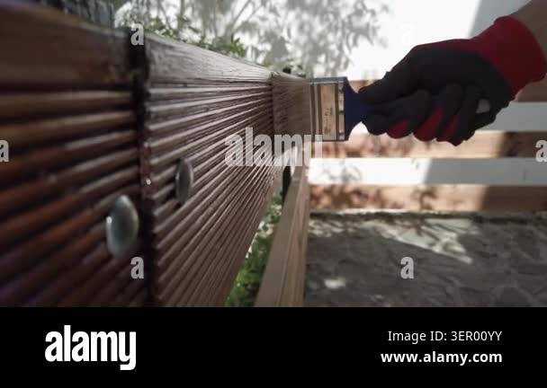 Hand in glove painting fence of impregnated ship floor planks ...