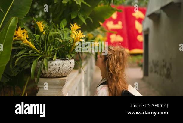 Young woman enjoying the beauty and fragrance of yellow flowers in a ...
