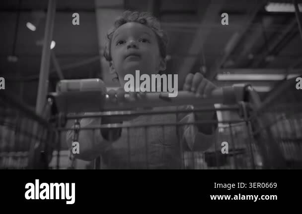 Low-angle view of a young curly-haired child standing inside a metal ...
