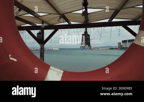 Bright orange lifebuoy hanging above calm harbor water, symbolizing ...