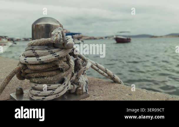 Close-up view of a harbor bollard wrapped with coiled rope, with ...