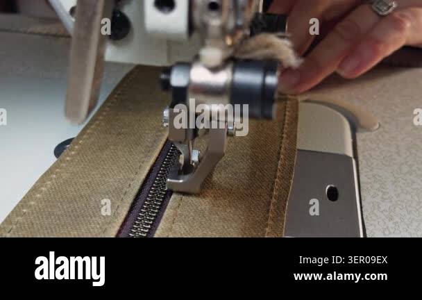 Close up view of a tailor sewing fabric on a sewing machine, focused on ...