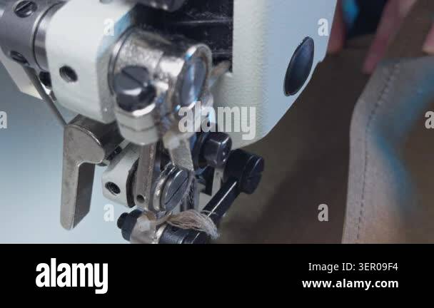 Close up view of a tailor sewing fabric on a sewing machine, focused on ...