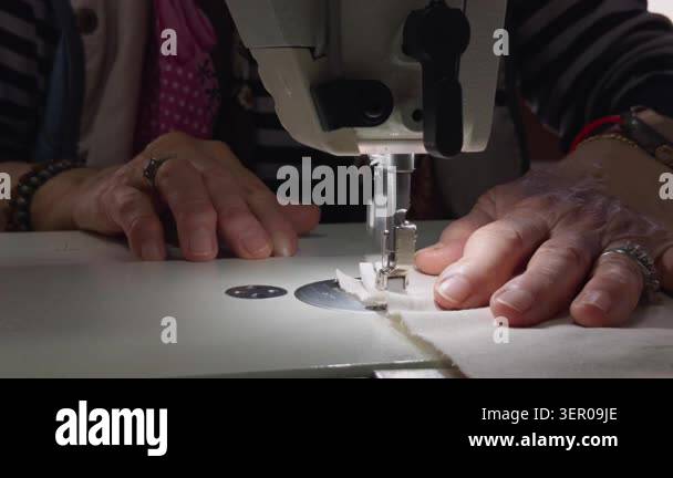 Close up view of a tailor sewing fabric on a sewing machine, focused on ...