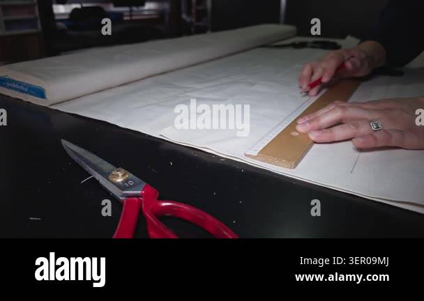 Close up view of a tailor marking fabric measurements using chalk and a ...