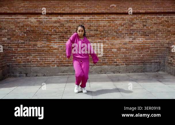 Energetic woman with braids performing a dynamic hip hop dance routine ...
