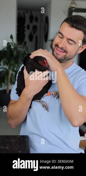 Vertical video showing a smiling man gently holding and petting a black ...