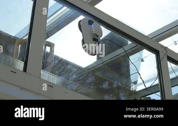 Automatic robot cleans a glass roof of a conservatory under bright ...