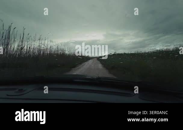 A moody landscape view of a wet asphalt road through a car window ...