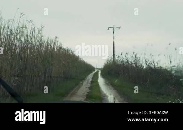 A moody landscape view of a wet asphalt road through a car window ...