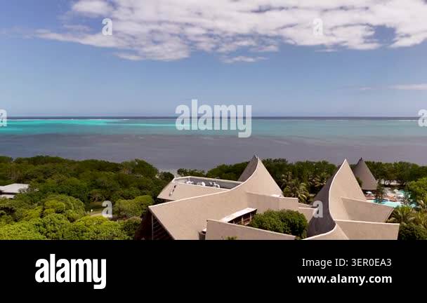 Aerial view of turquoise lagoon, resort roofs with pointed thatched ...