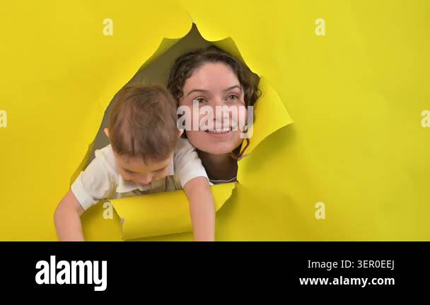 Cheerful young mother with curly brown hair and her toddler son wearing ...