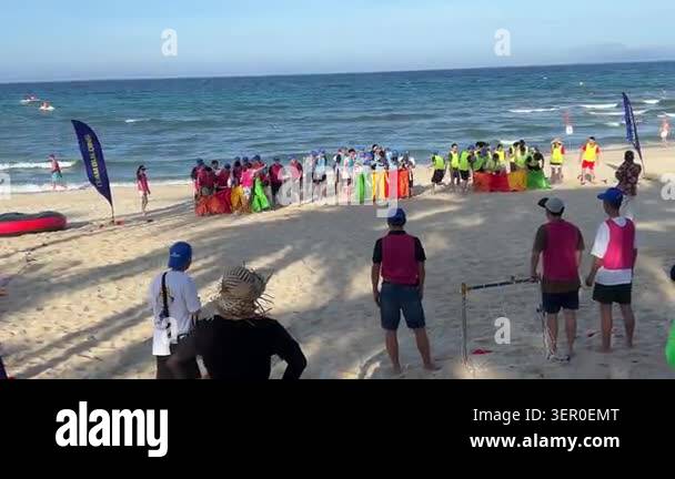 Participants in colorful team outfits run, jump and compete in beach ...