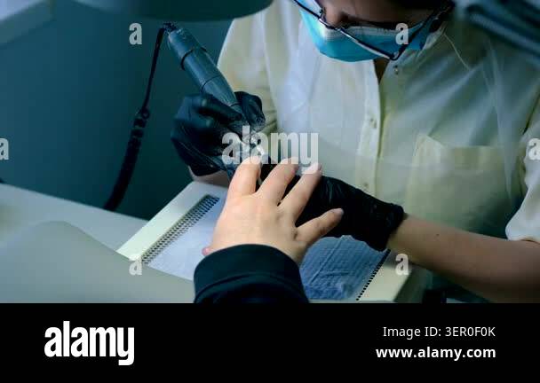 Technician in black gloves rubs nourishing cream into female hands post ...