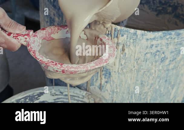 Process of filtering liquid ceramic slurry through a mesh strainer into ...