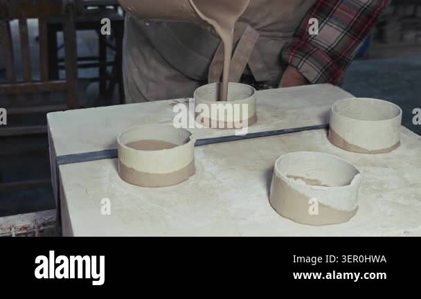 Professional shot of pouring liquid clay slip into a plaster mold ...