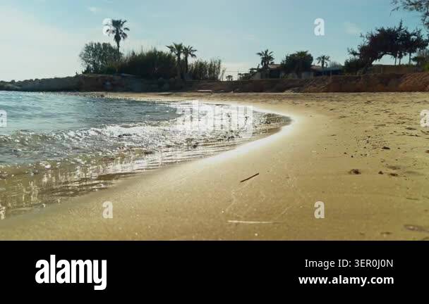 High resolution cinematic shot of gentle sea waves crashing on a golden ...