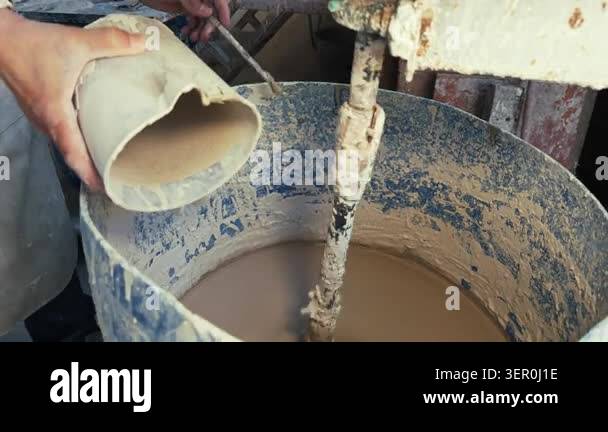 Close-up of liquid clay mud swirling in an industrial mixer within a ...