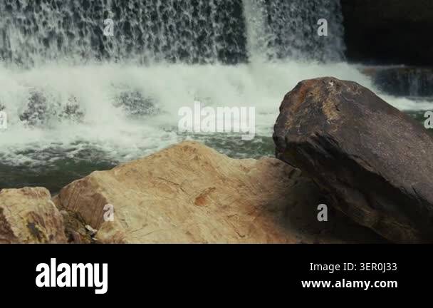Wide scenic shot of a powerful waterfall cascade flowing into a rocky ...