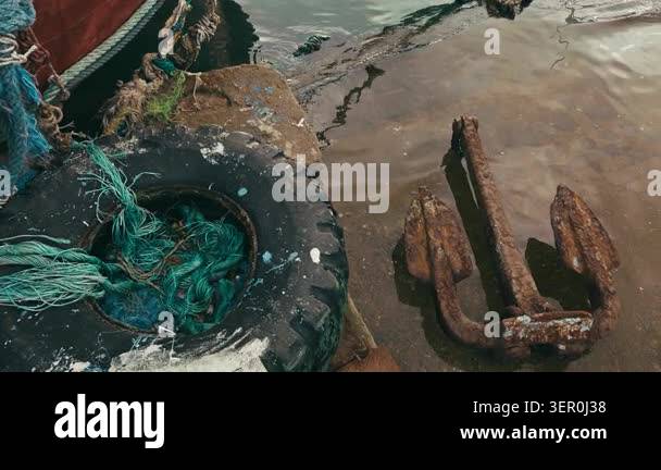 A large rusty ship anchor rests on the water surface, symbolizing ...