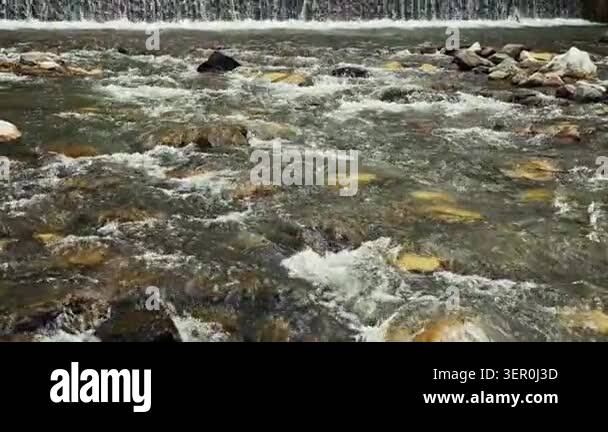 Wide scenic shot of a powerful waterfall cascade flowing into a rocky ...