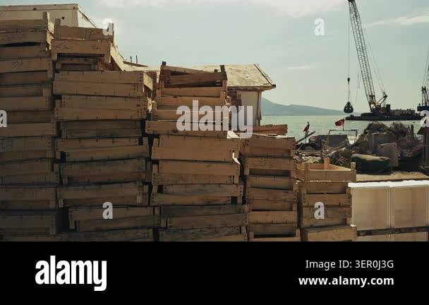 High resolution cinematic shot of stacked empty wooden fish crates at a ...