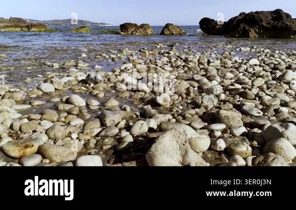 High resolution cinematic shot of little pebbles on the shoreline near ...