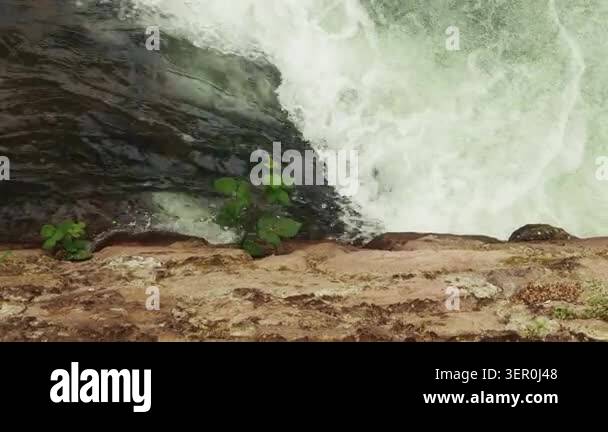 Wide scenic shot of a powerful waterfall cascade flowing into a rocky ...