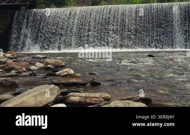 Wide scenic shot of a powerful waterfall cascade flowing into a rocky ...