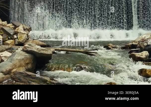 Wide scenic shot of a powerful waterfall cascade flowing into a rocky ...