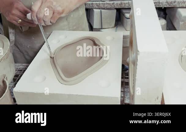 Close up of a ceramic artisan working with plaster molds in a pottery ...