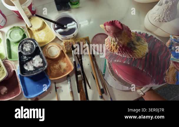 Close up of an artisan hand painting a handmade ceramic chicken ...