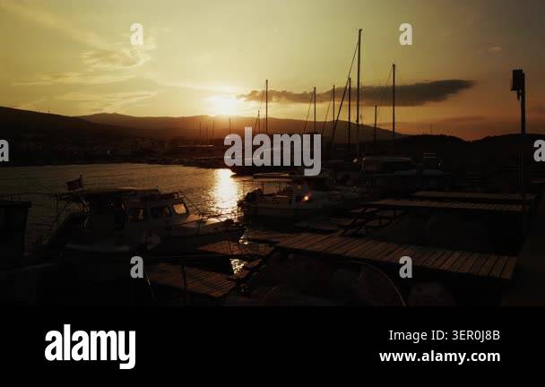 Cinematic wide shot of a calm marina harbor at sunset featuring ...