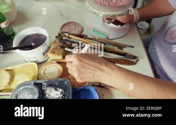 Close up of an artisan hand painting a handmade ceramic chicken ...
