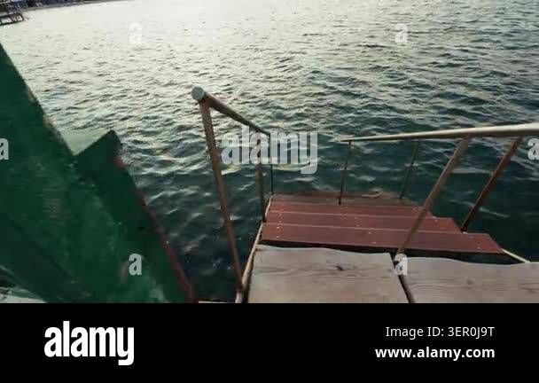 High angle shot of a wooden pier ladder with metal handrails leading ...