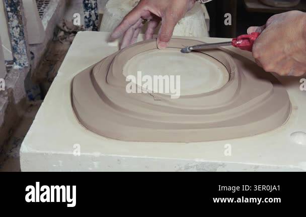 Close up of a ceramic artisan working with plaster molds in a pottery ...
