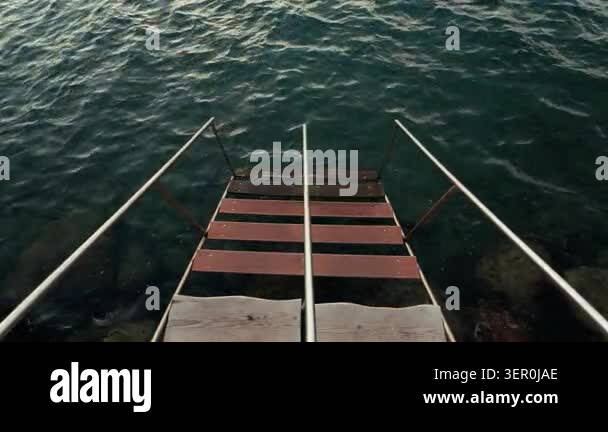High angle shot of a wooden pier ladder with metal handrails leading ...