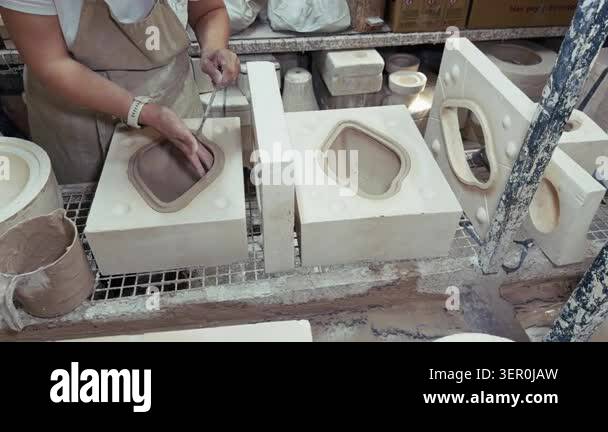 Close up of a ceramic artisan working with plaster molds in a pottery ...