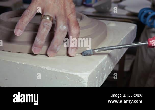 Close up of a ceramic artisan working with plaster molds in a pottery ...