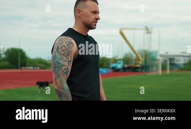 Steadicam follow shot of an athletic man running on a stadium track in ...