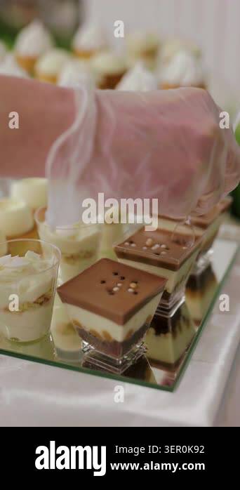Close-up of waiter in gloves preparing chocolate layered verrines for a ...