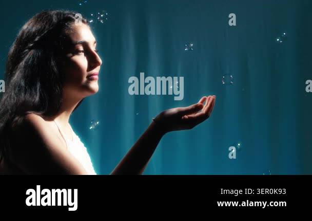 Young woman fascinated by soap bubbles in a dreamy room, smiling and ...
